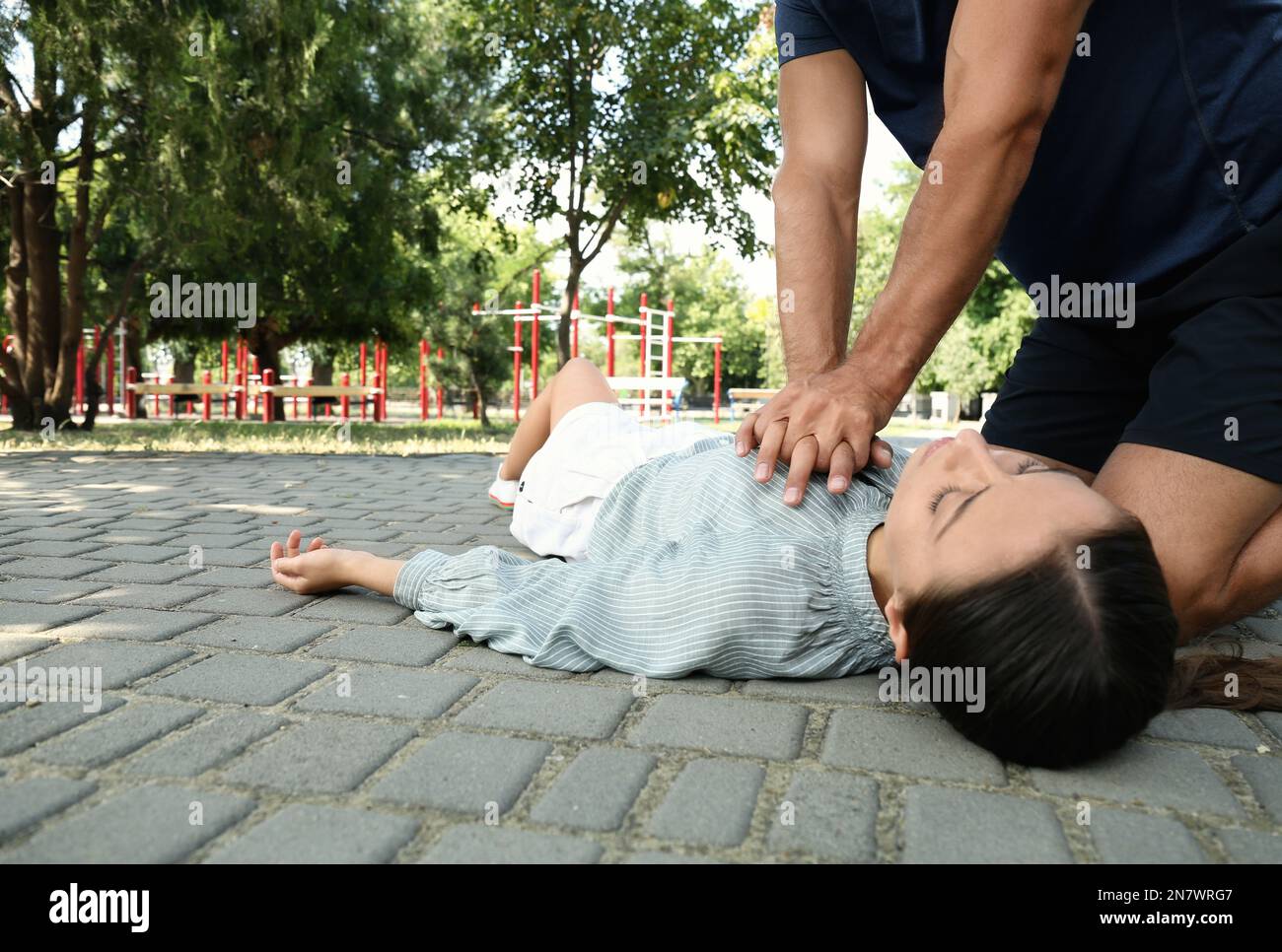Man performing CPR on unconscious young woman outdoors. First aid Stock ...