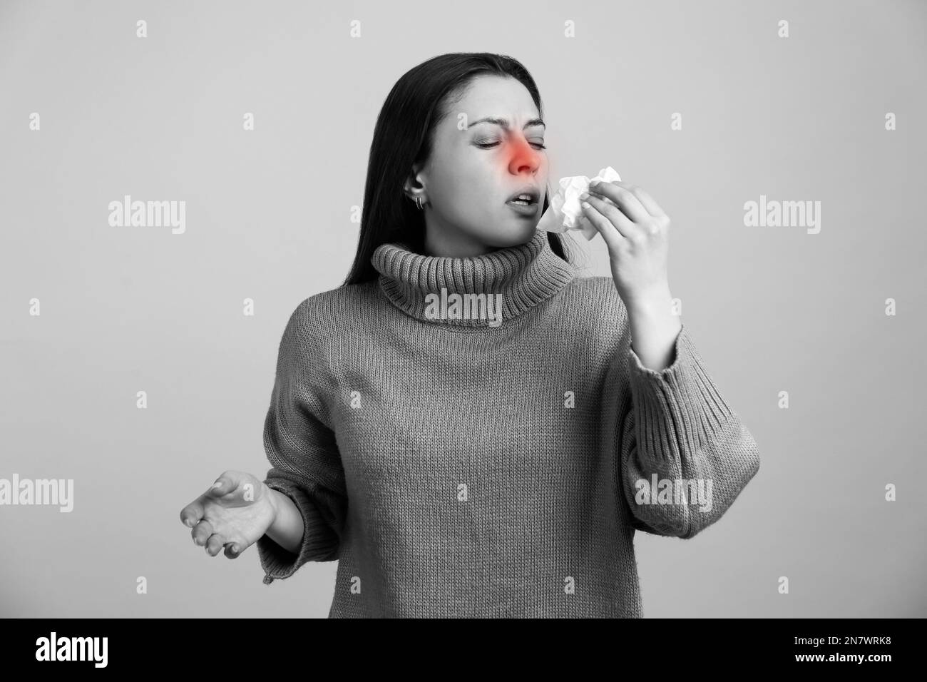 Young woman with tissue sneezing on light background, toned in black ...