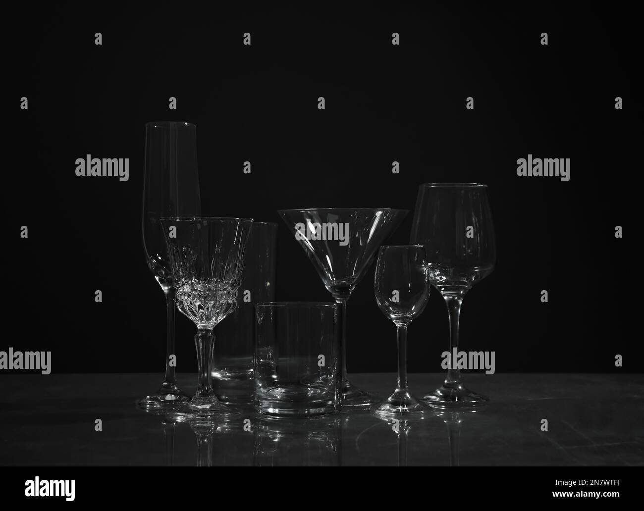 Set of bar glassware on table against dark background Stock Photo - Alamy