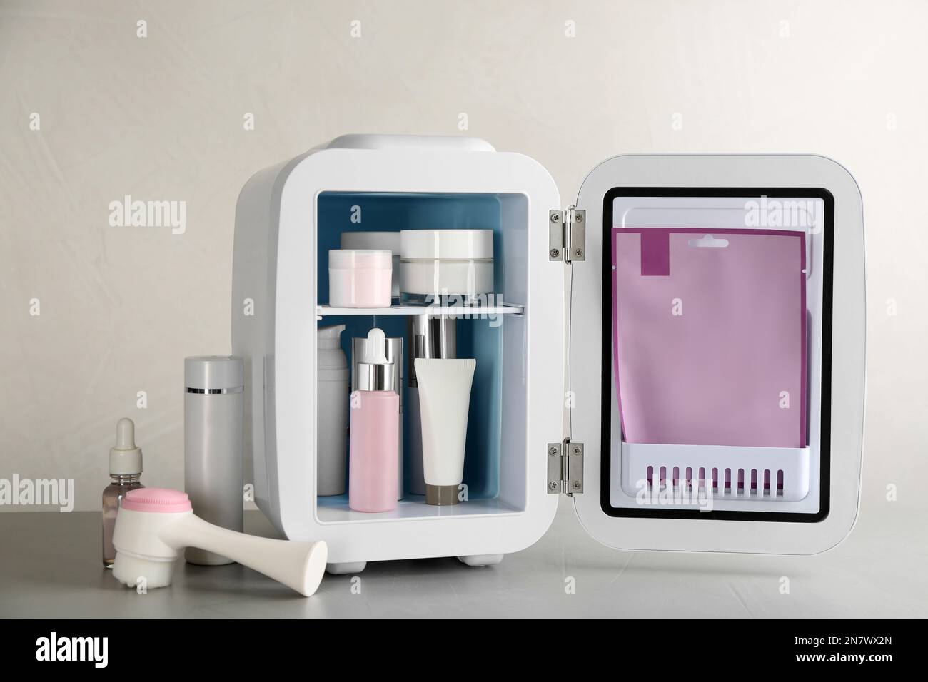 Open cosmetic refrigerator and skin care products on beige background ...