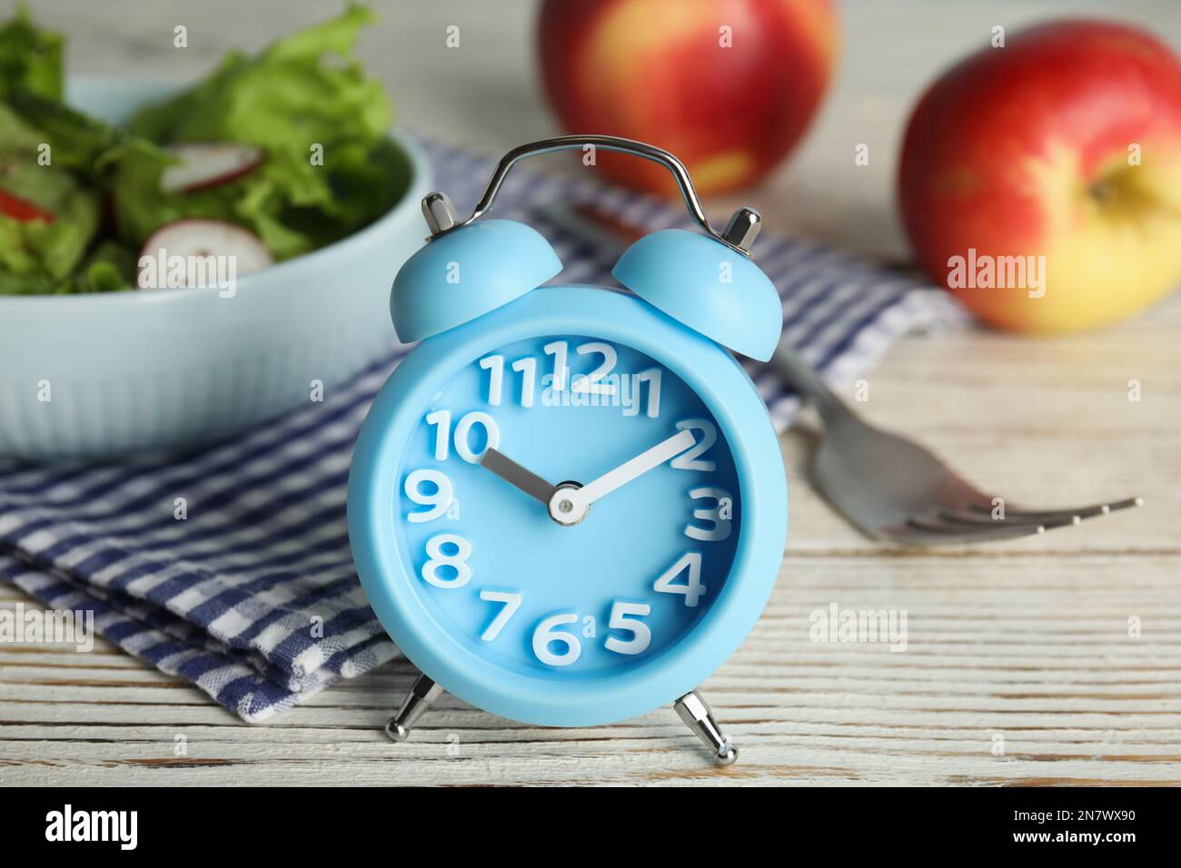 Alarm clock and healthy food on white wooden table, closeup. Meal ...