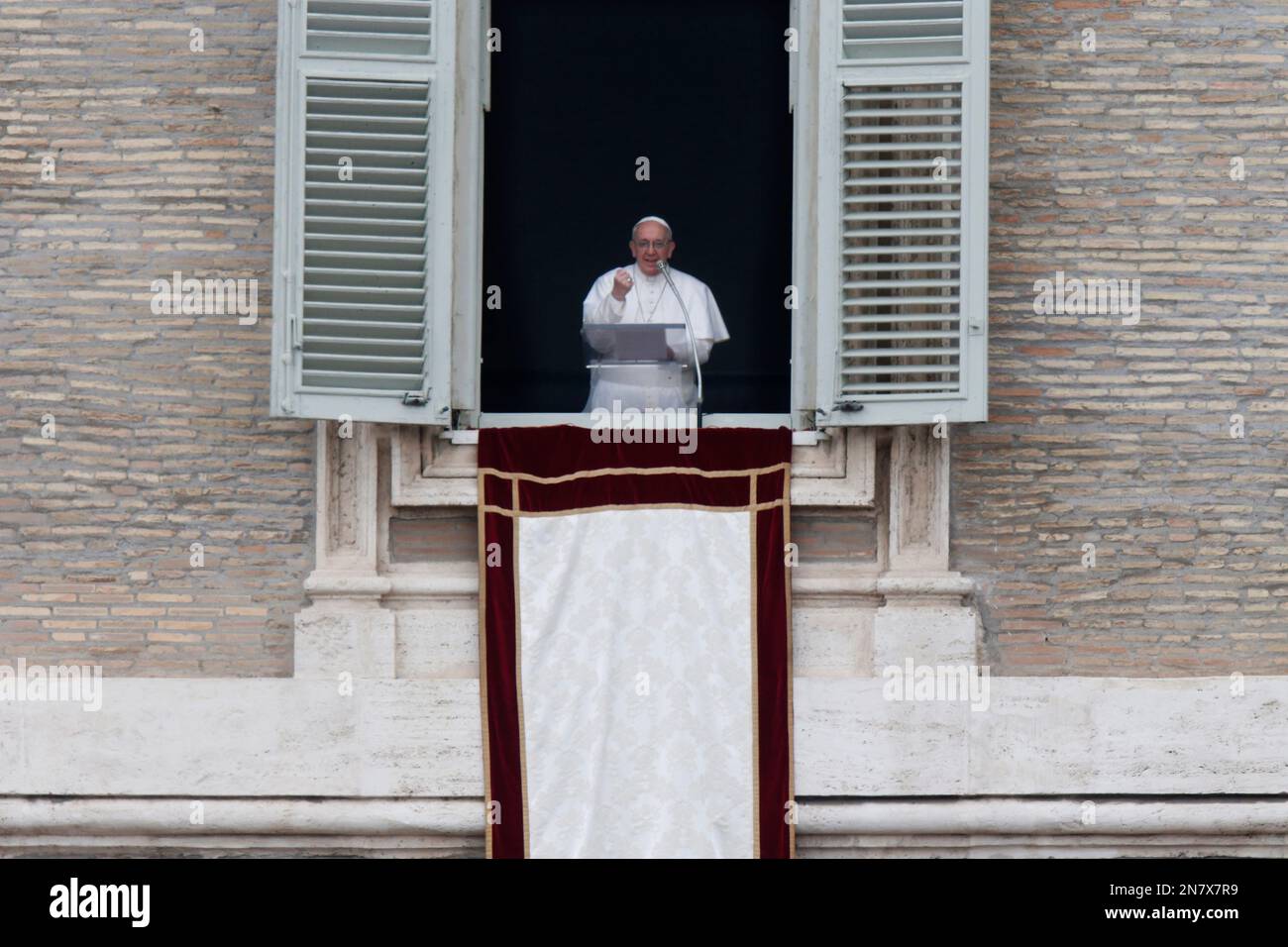 Pope Francis speaks to the crowd in St. Peter's Square from the window ...