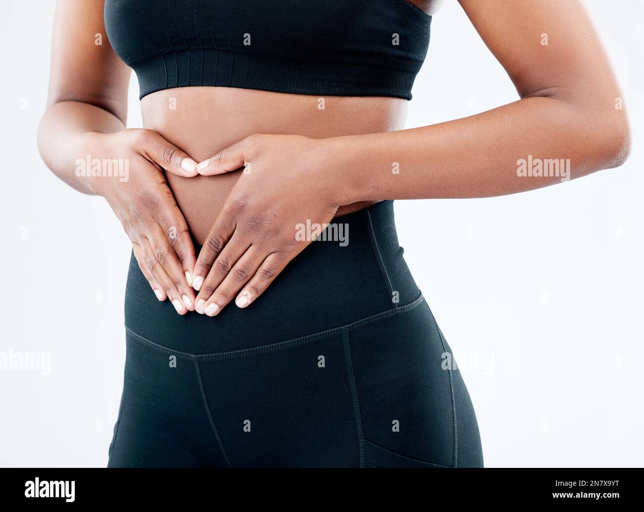 Trust your gut. a sporty young woman forming a heart shape over her ...