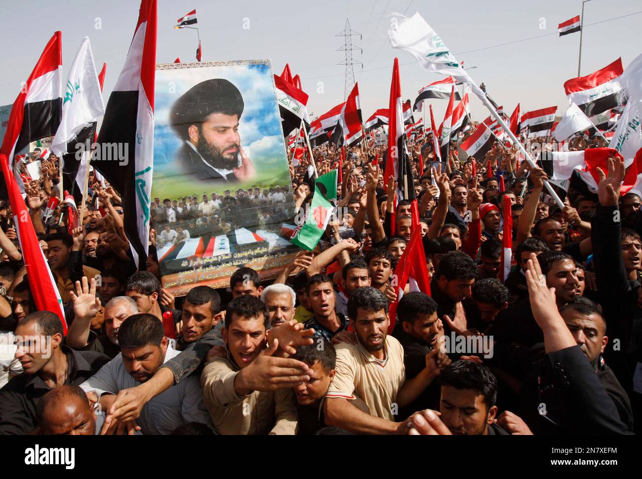 Followers of Shiite cleric Muqtada al-Sadr carry a poster with his ...