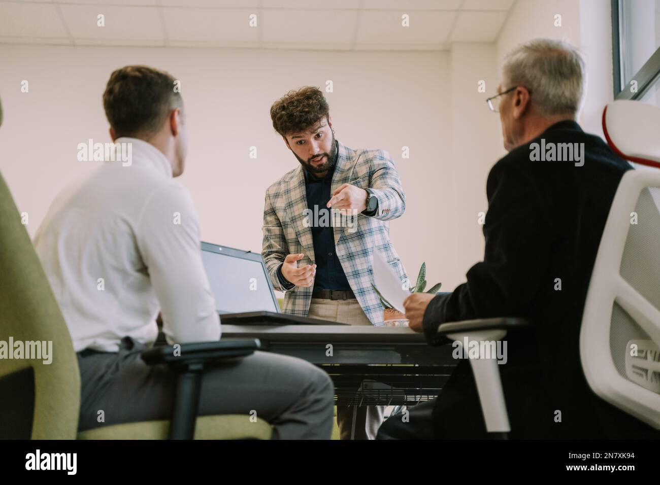 Disappointed and angry boss overlooking and correcting his employees at ...