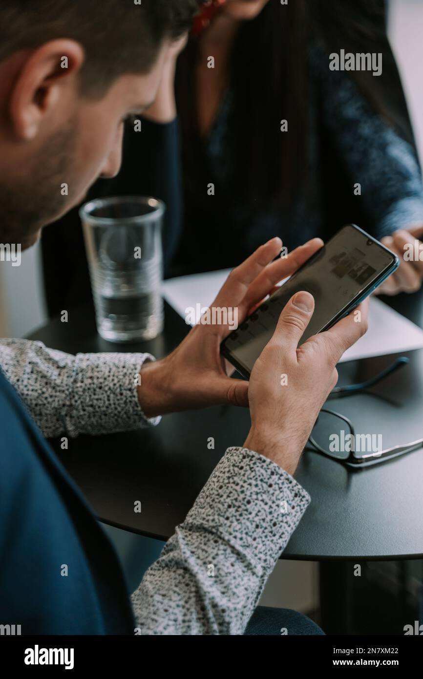 A close up photo of a young businessman scrolling on social medias at ...