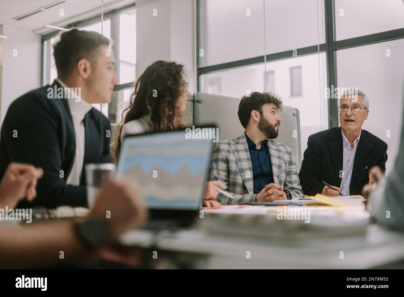 Multi-generational co working at the office. Older businessman advising ...