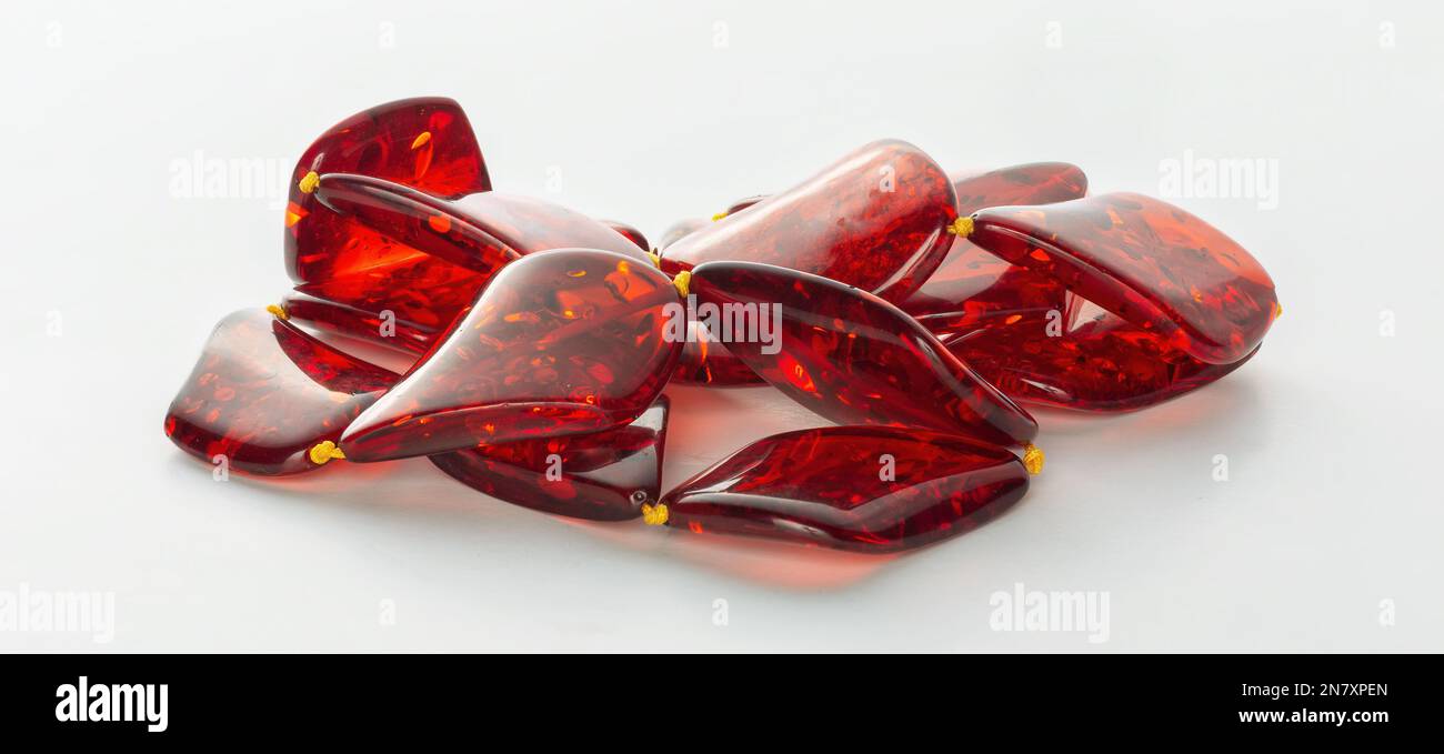 Transparent polished beads of red amber on a white background. Sun stone. Natural mineral ...