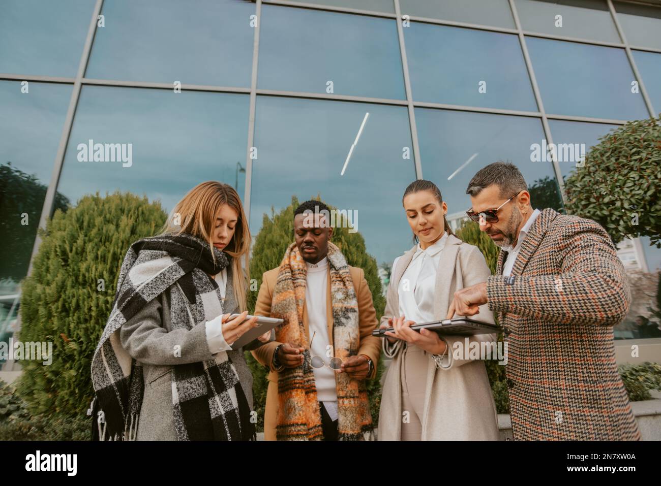 Four business colleagues working outside in front of the building and ...