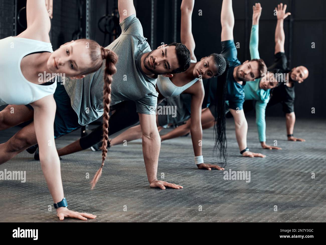 Believe in your inner warrior. a group of gym friends side planking ...