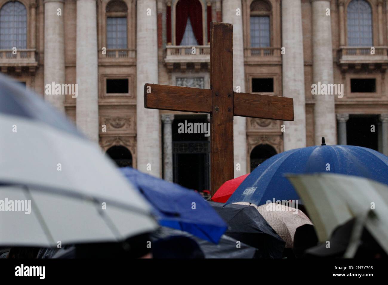 Pilgrims hold a cross in front of St. Peter's Basilica while cardinals ...