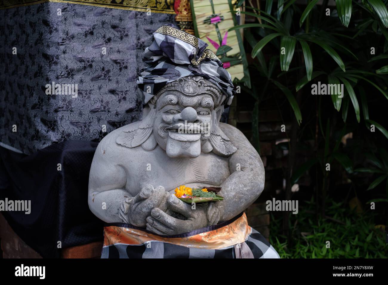 The gate guard statue is made of stone covered by Balinese sacred cloth ...