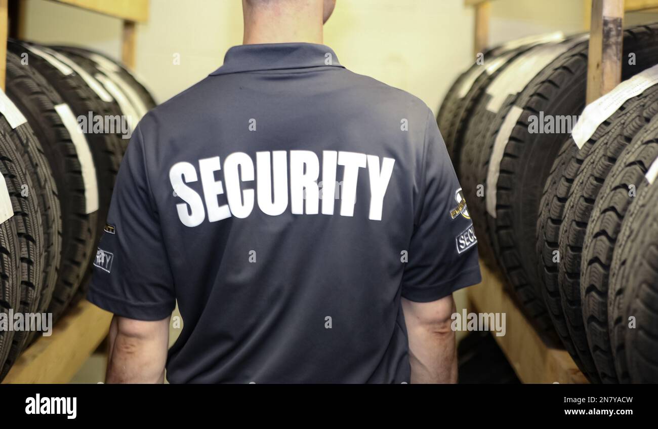 A back of a security guard patrolling inside the warehouse of tires ...