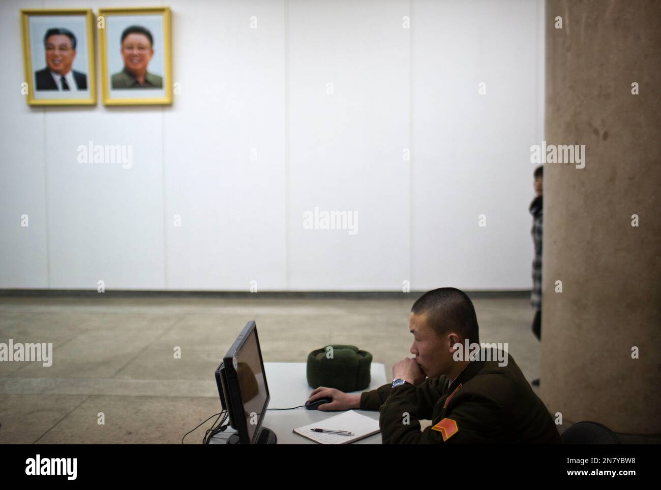 A North Korean soldier works at a computer terminal under portraits of ...