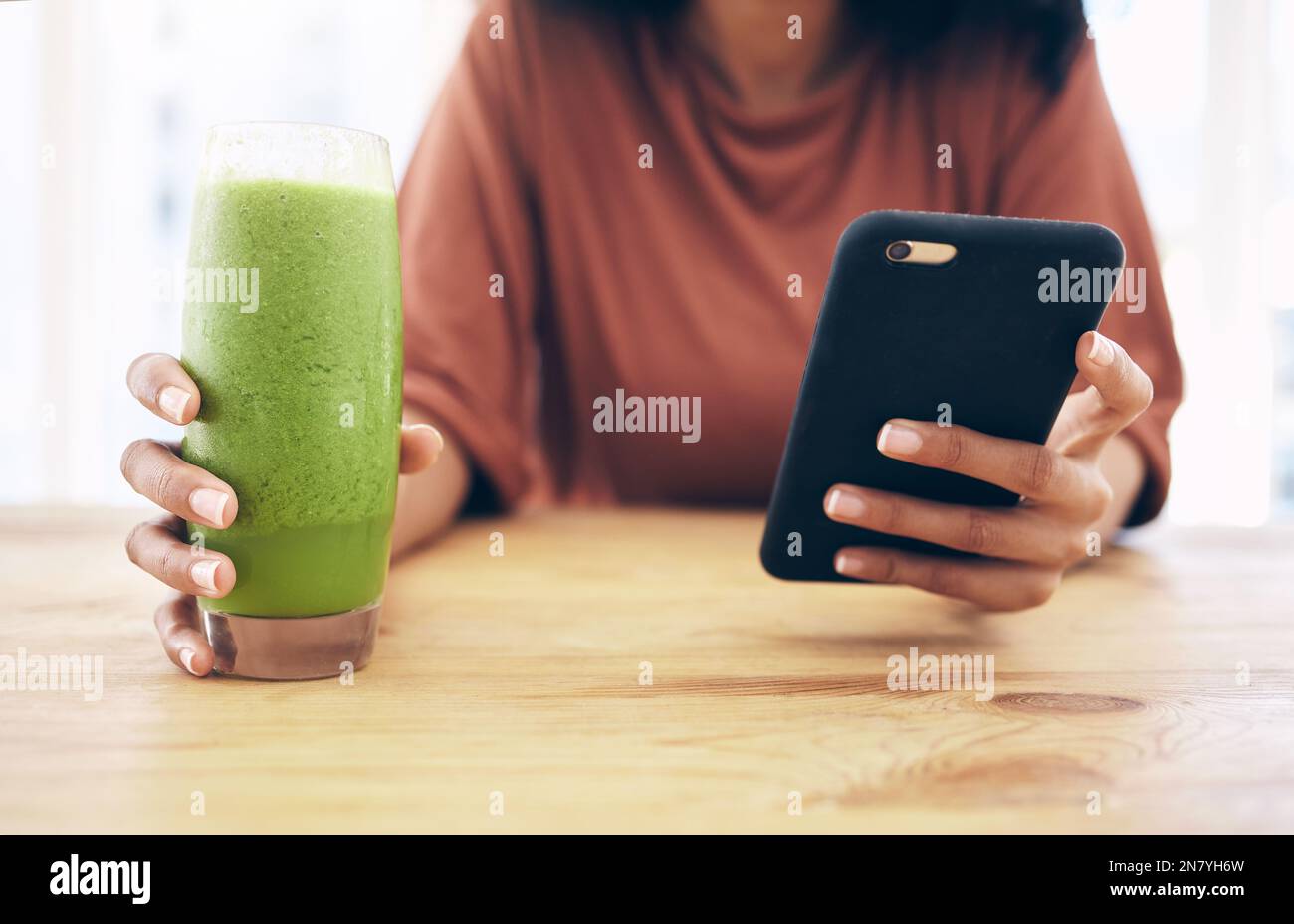 Hands, glass and phone with a black woman in the kitchen of her home ...