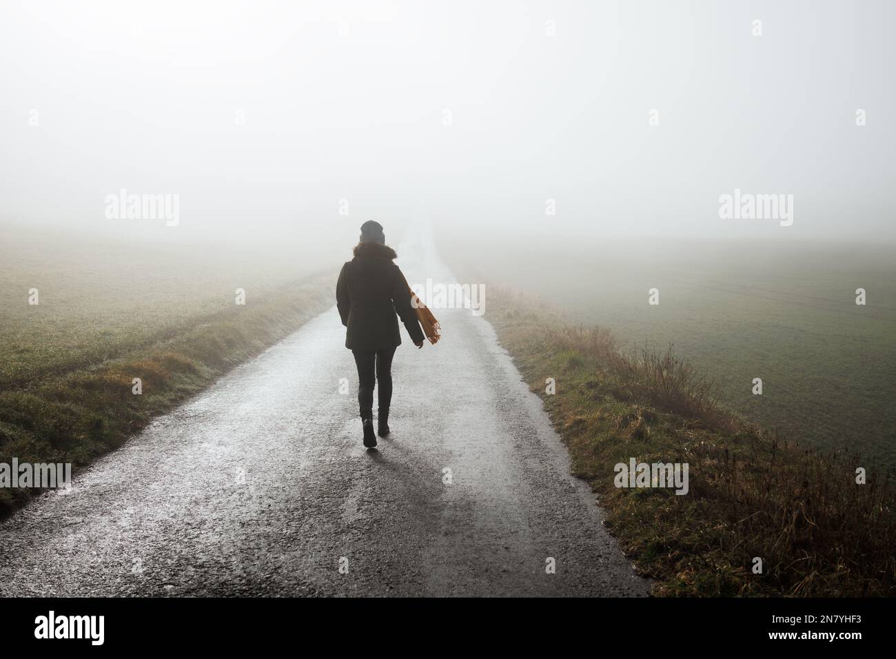 Lonely courageous woman walks on empty road in fog. Journey to unknown ...