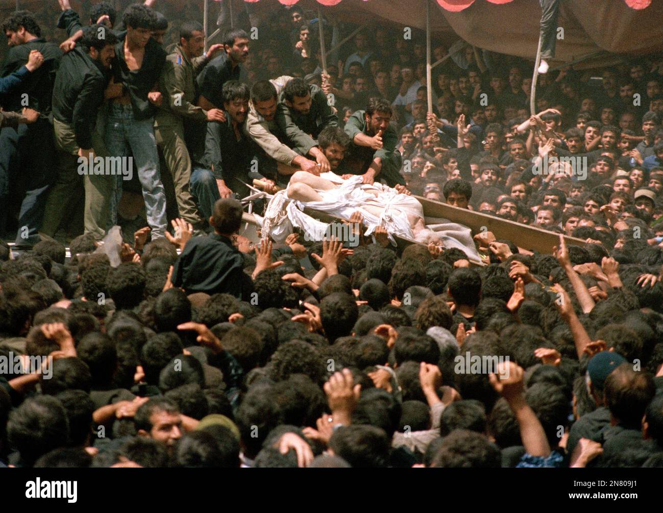 A mass of hysterical mourners reach out to touch the body of Iran's ...