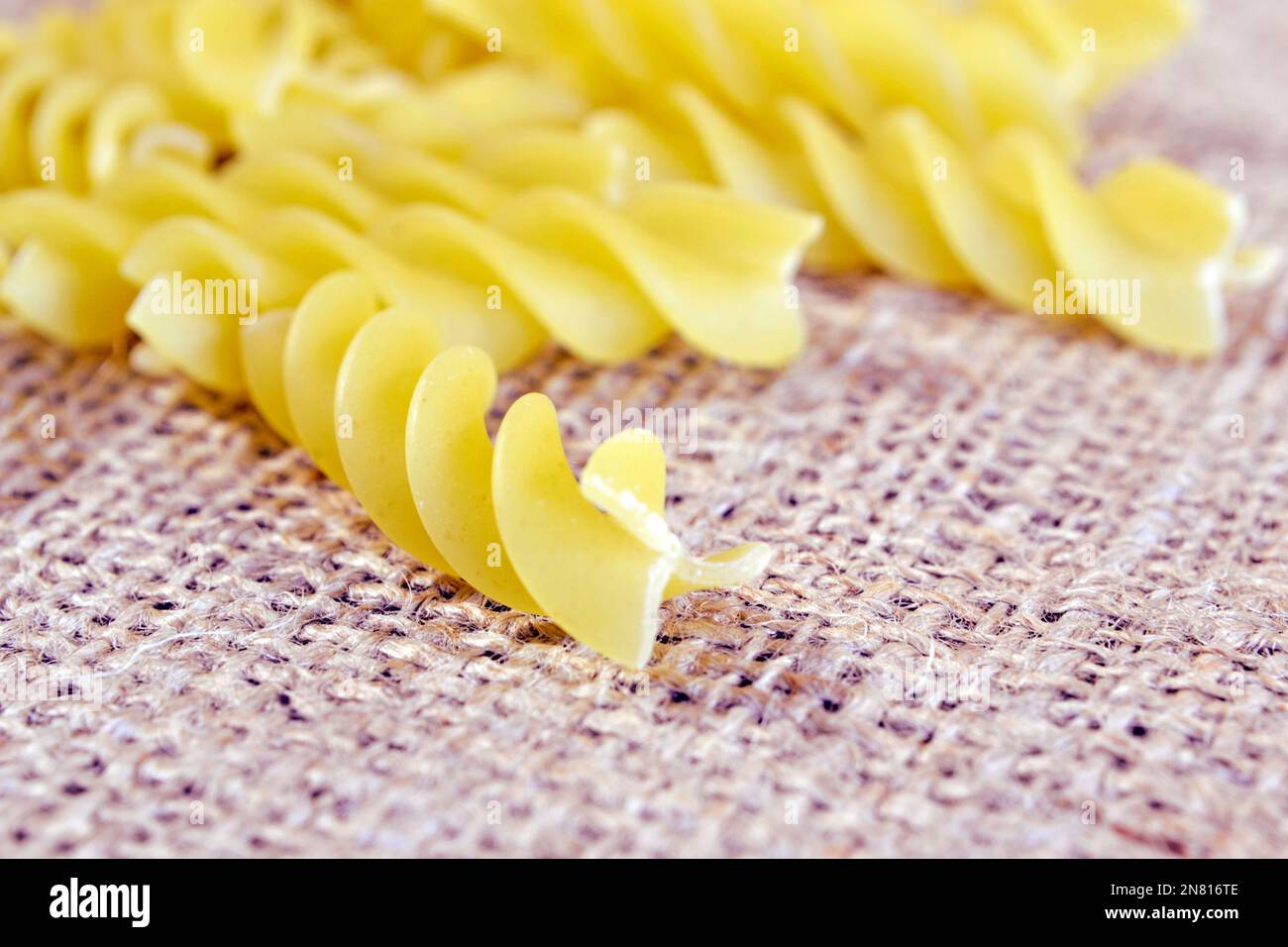 Italian food: raw fusilli pasta on jute Stock Photo - Alamy