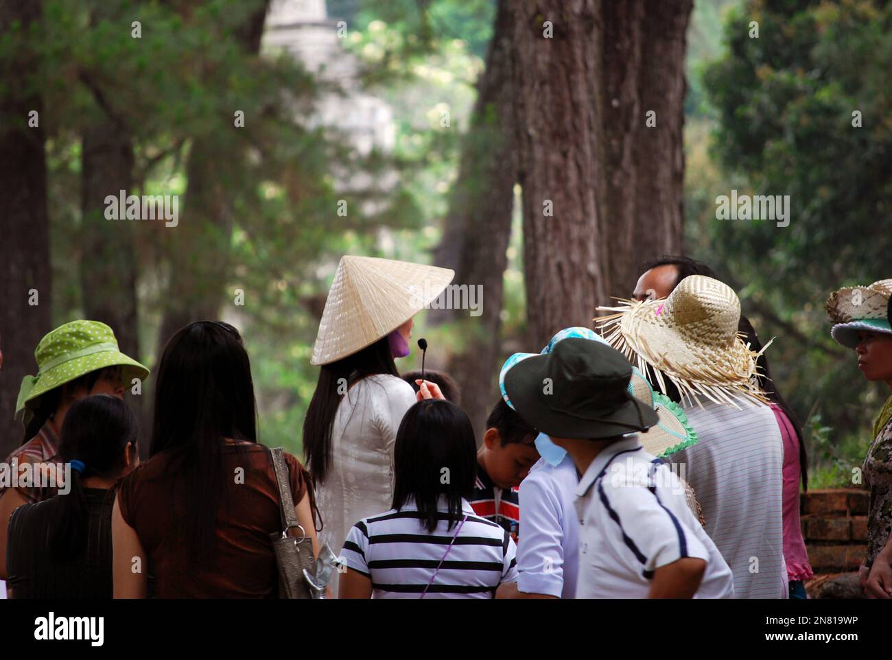 Tour guide with typical Vietnamese hat is speaking into the microphone ...