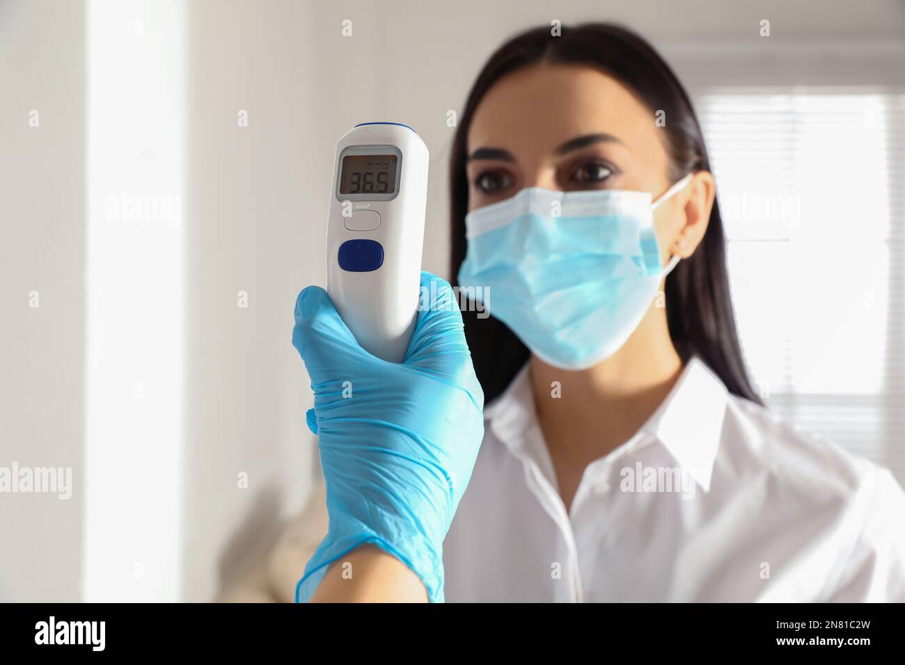 Doctor measuring woman's temperature in office, closeup. Prevent ...
