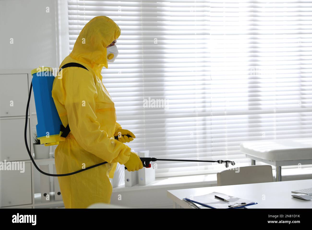 Man in protective suit sanitizing doctor's office. Medical disinfection ...