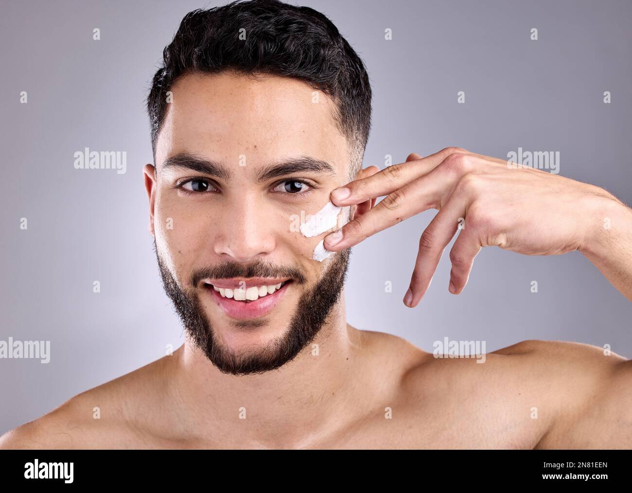 My skin just look and feels better after moisturising. a handsome young man applying lotion to ...