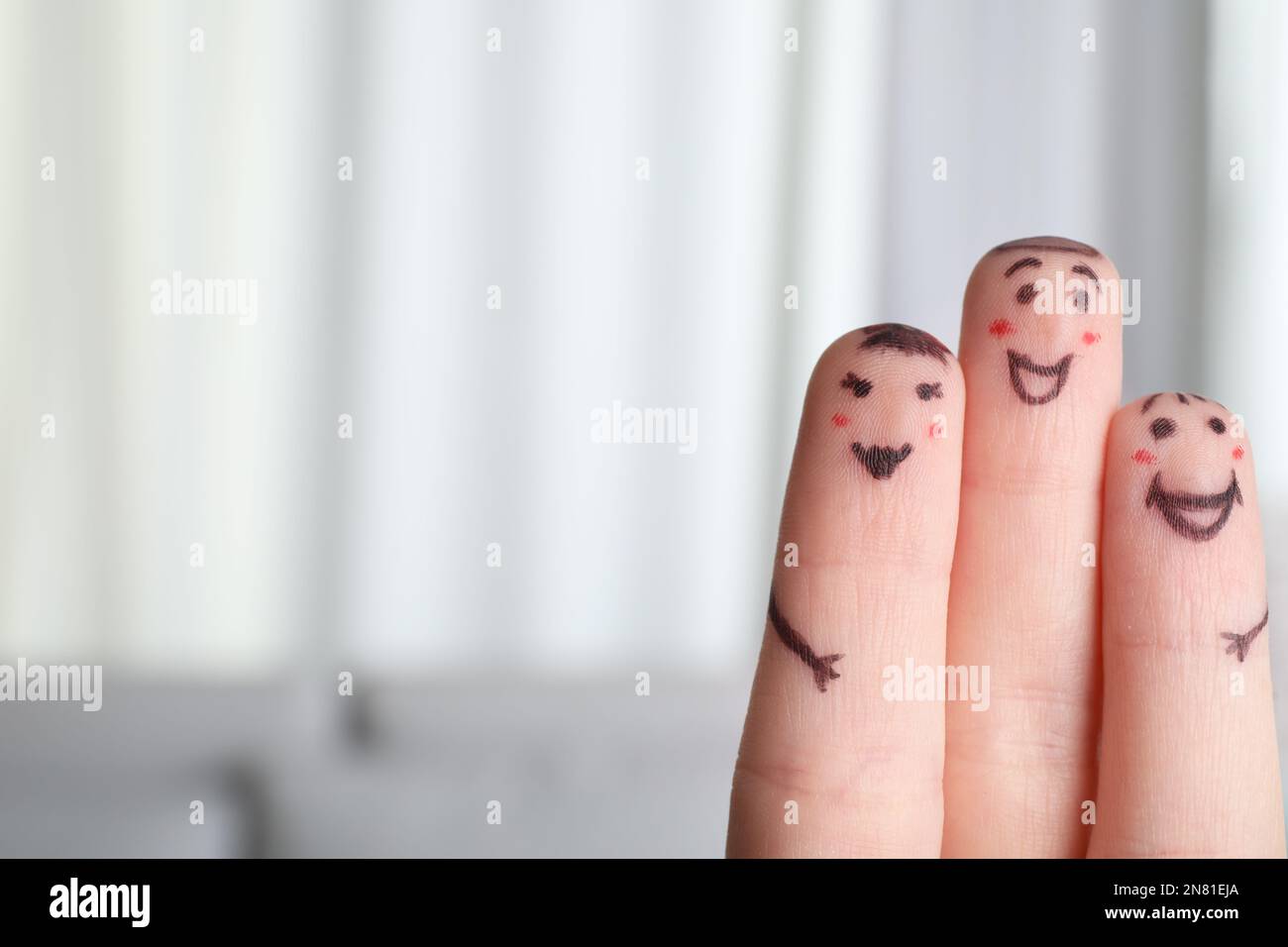 Three fingers with drawings of happy faces on blurred background, space ...