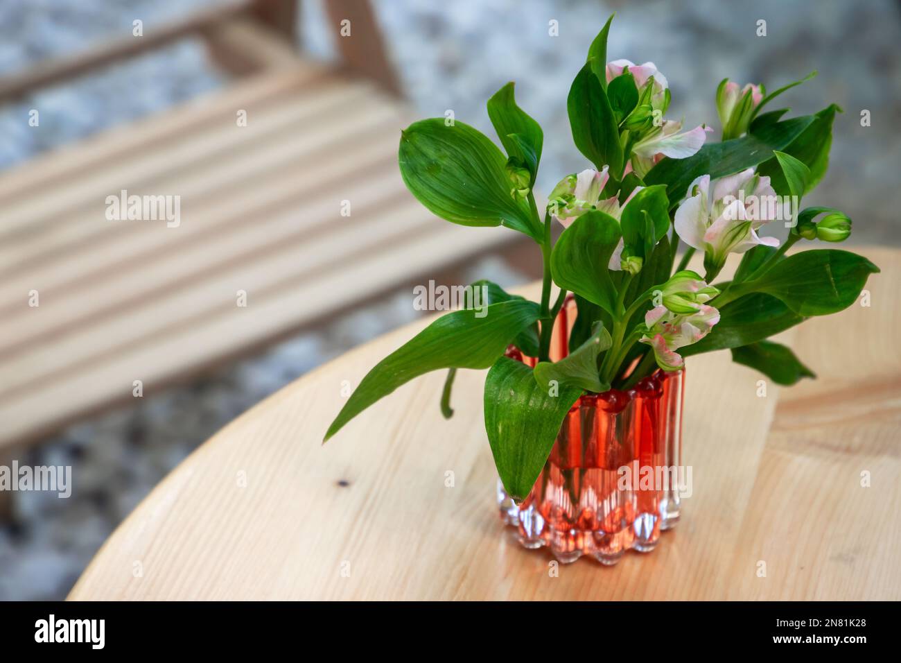 Small bouquet of flowers stand in a glass vase on a wooden table ...