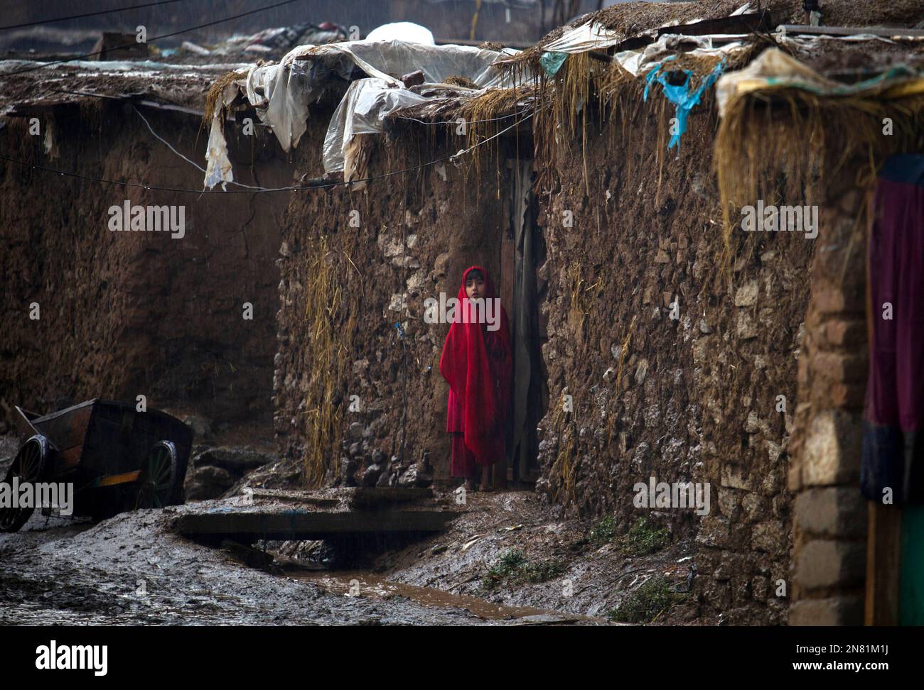 A Pakistani girl stands outside her home during a rainfall in a suburb ...