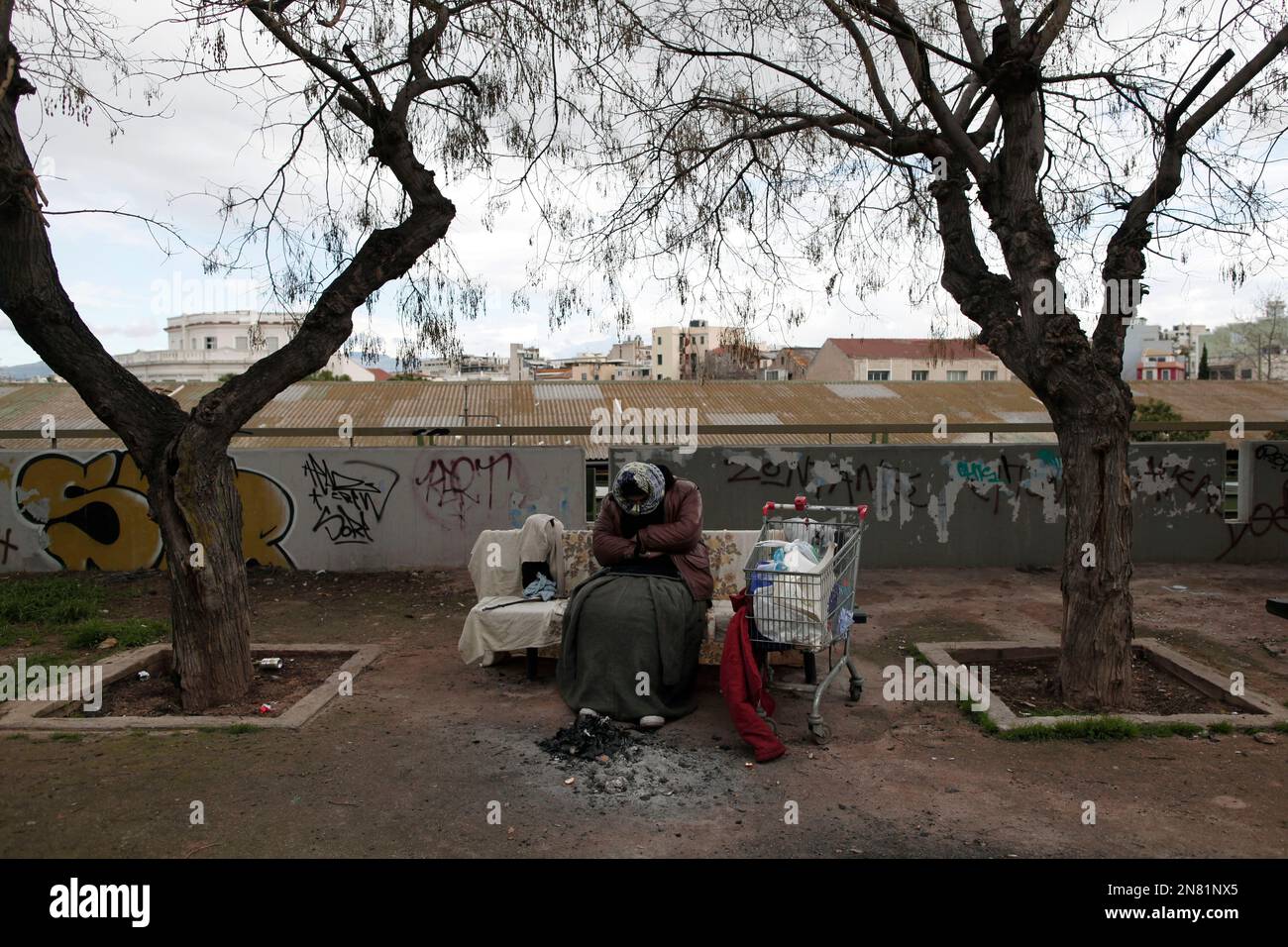 A homeless woman sits on a bench next to her belongings, in central ...