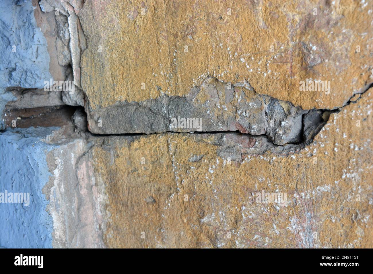 The old shabby walls of the old house, hewn with peeling paint, large and small cracks in the ...