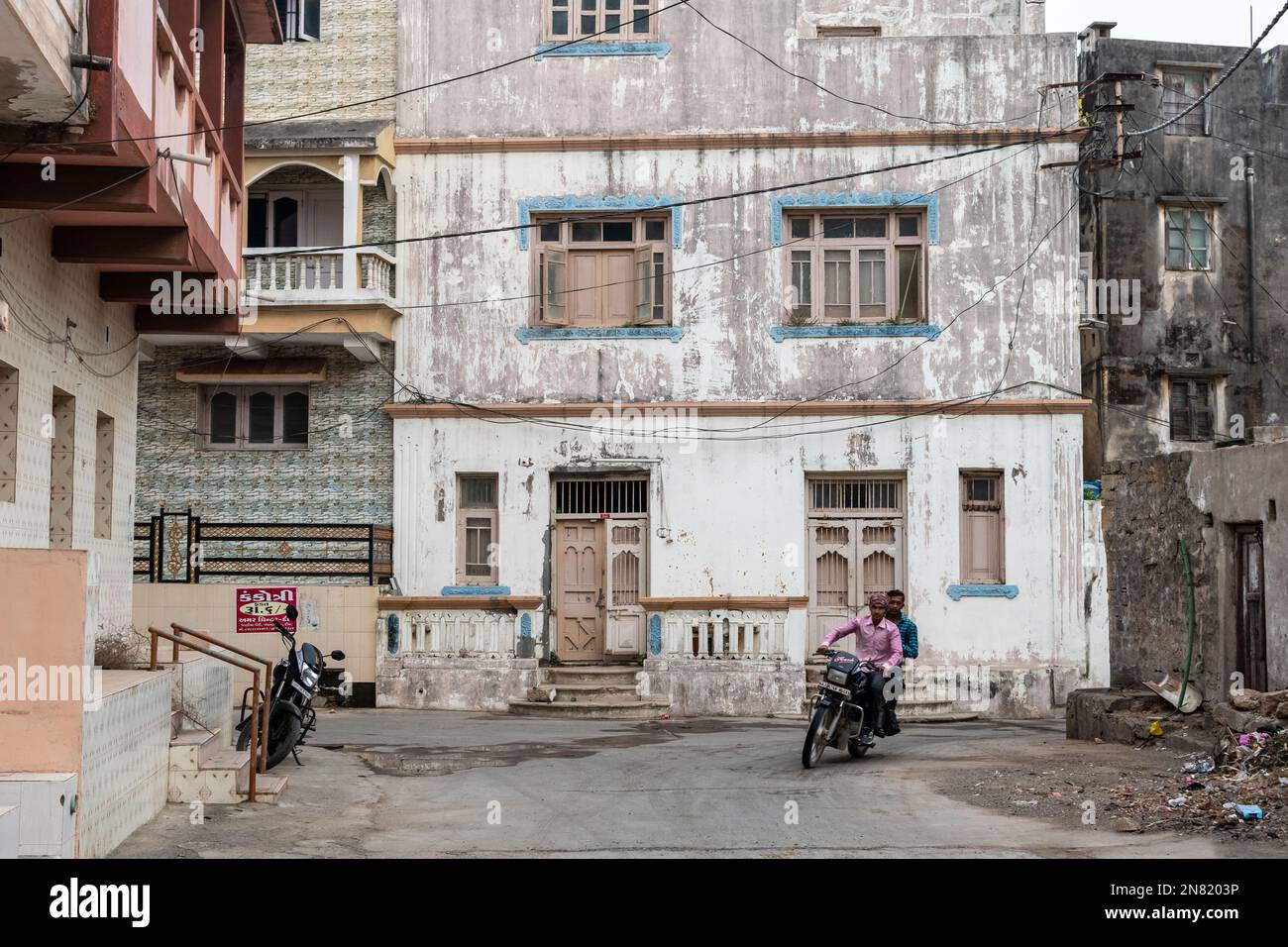 Diu, India - December 2018: A man riding a motorbike on a street lined ...