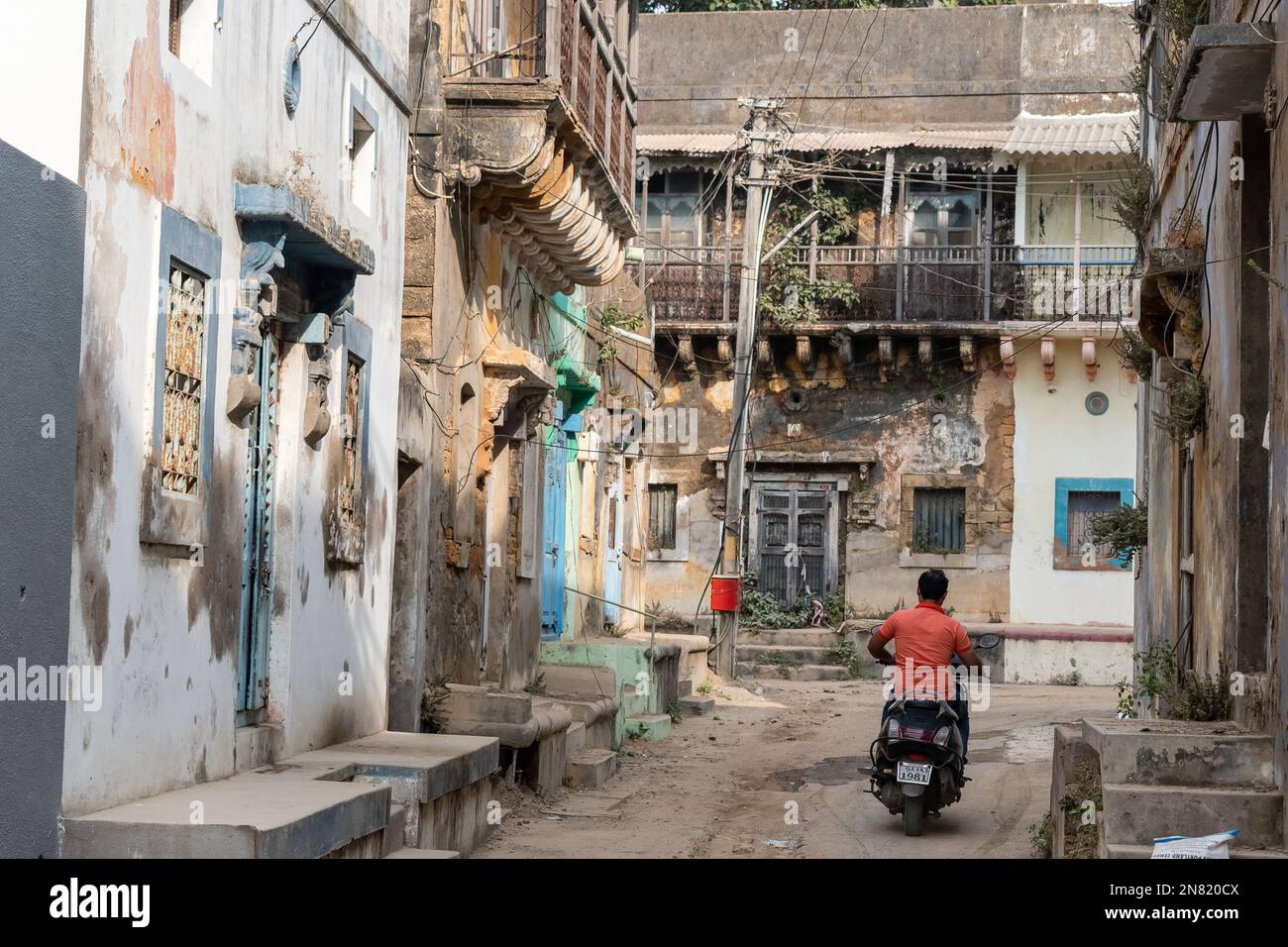 Diu, India - December 2018: A man riding a motorbike on a street lined ...