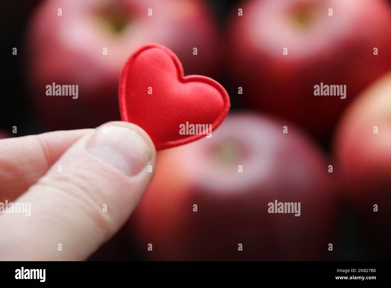 Healthy food idea. Hand holding a heart on the background of an apple ...
