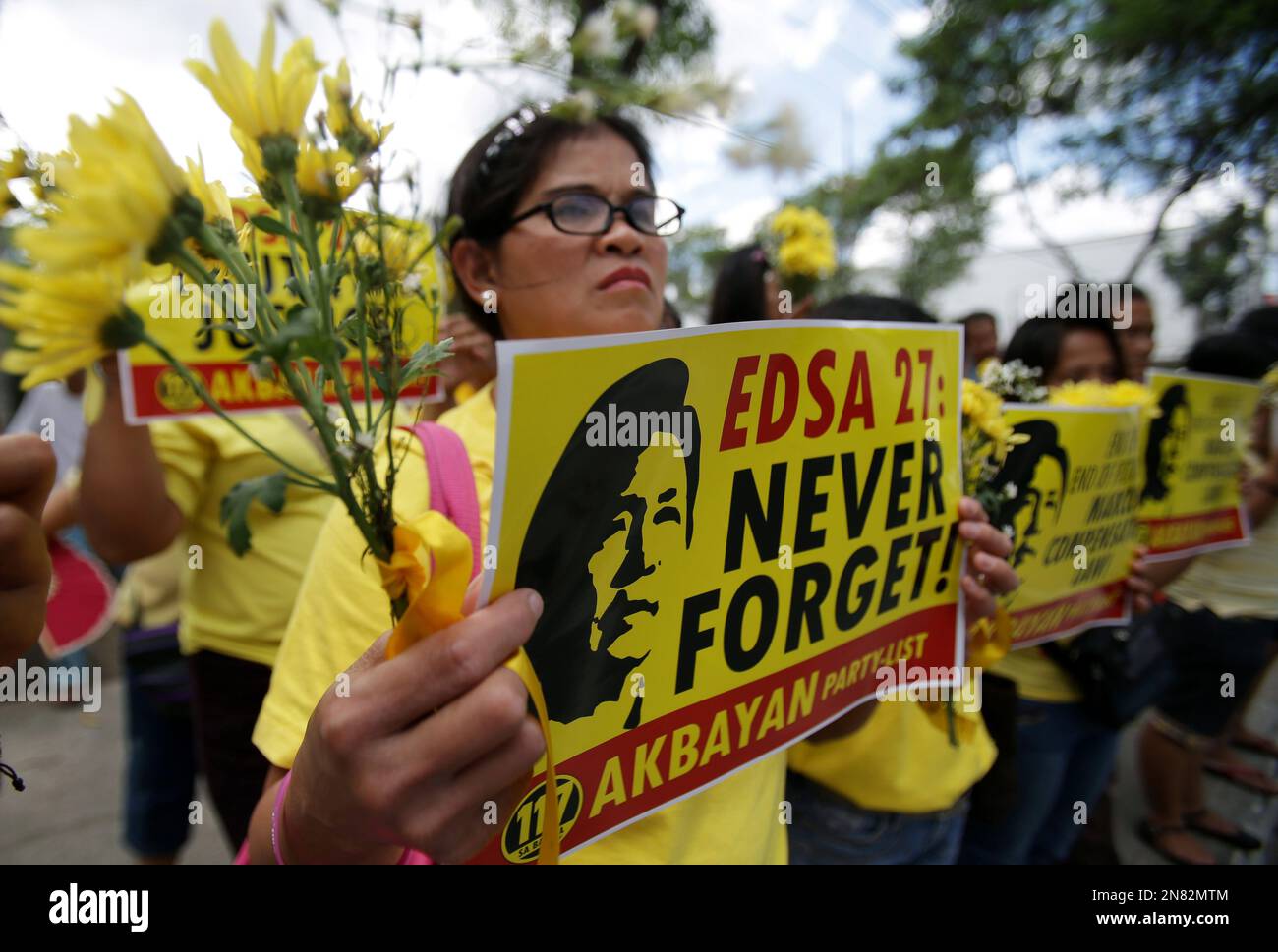 A Filipino activist displays flowers and slogans bearing an image of ...