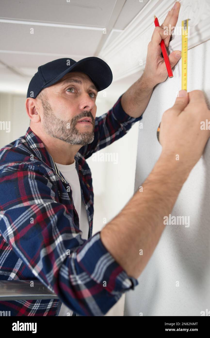 man measuring vertical linearity of installation of stucco relief Stock ... man measuring vertical linearity of installation of stucco relief Stock ...