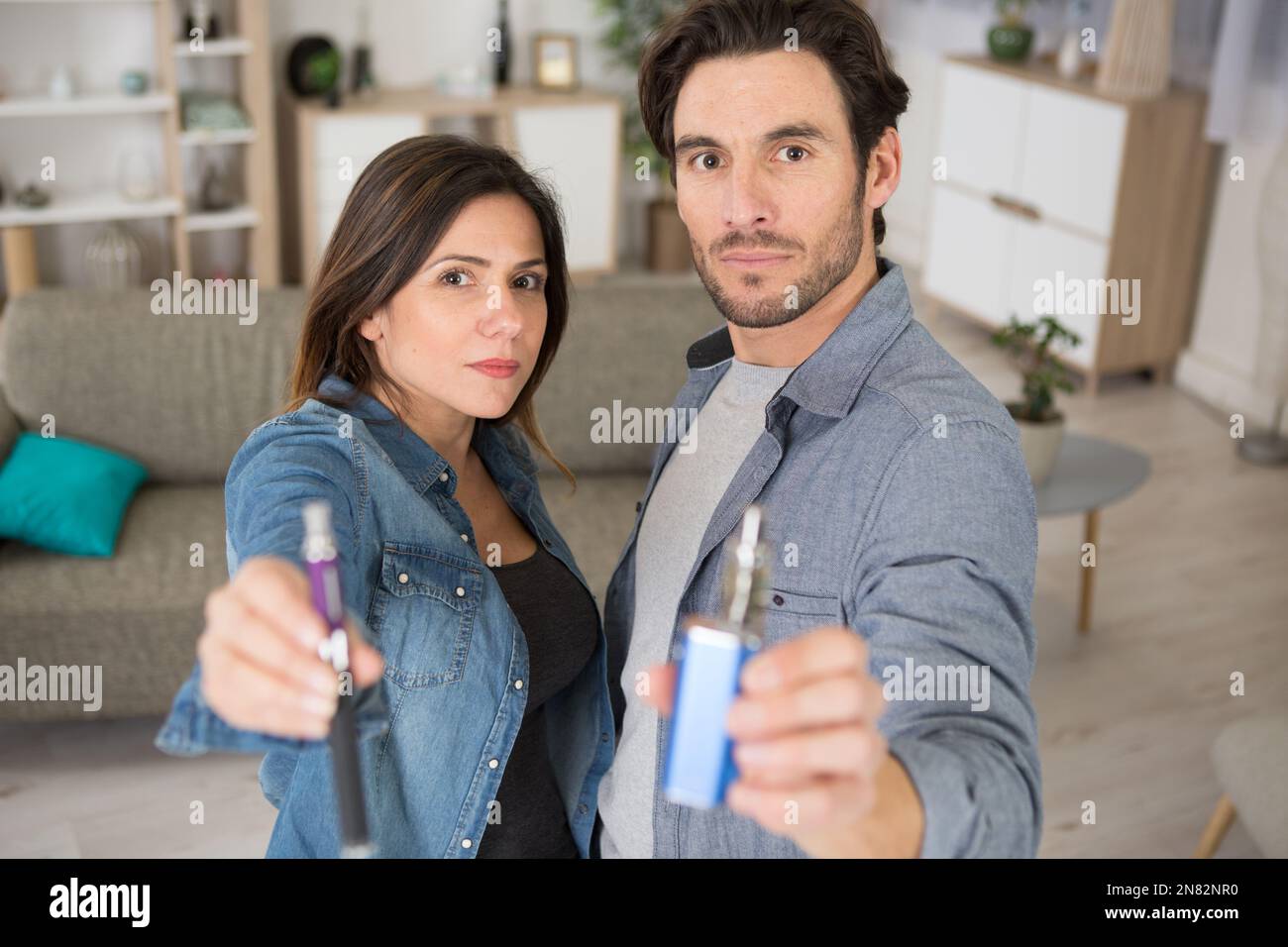 a serious couple holding vapes Stock Photo - Alamy