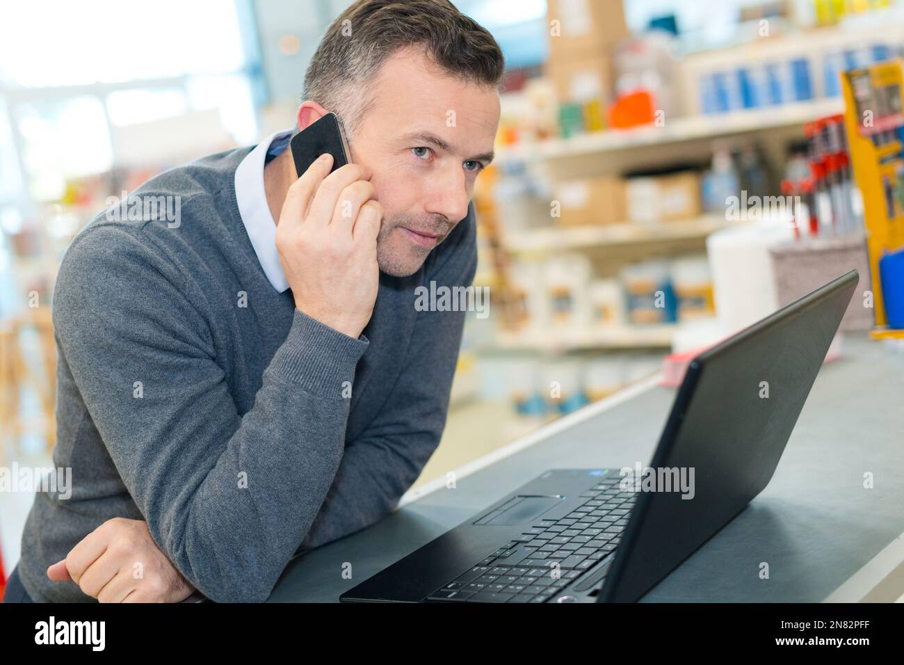 warehouse manager using telephone and laptop at desk Stock Photo - Alamy