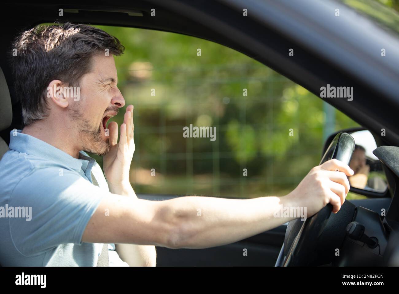 tired man is yawning while driving Stock Photo - Alamy