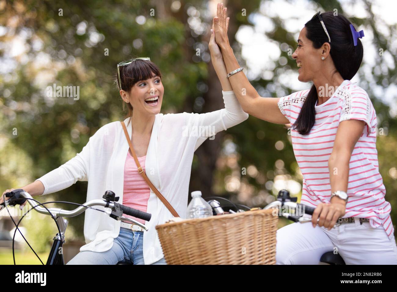 two women on bicycles doing a high-five Stock Photo - Alamy
