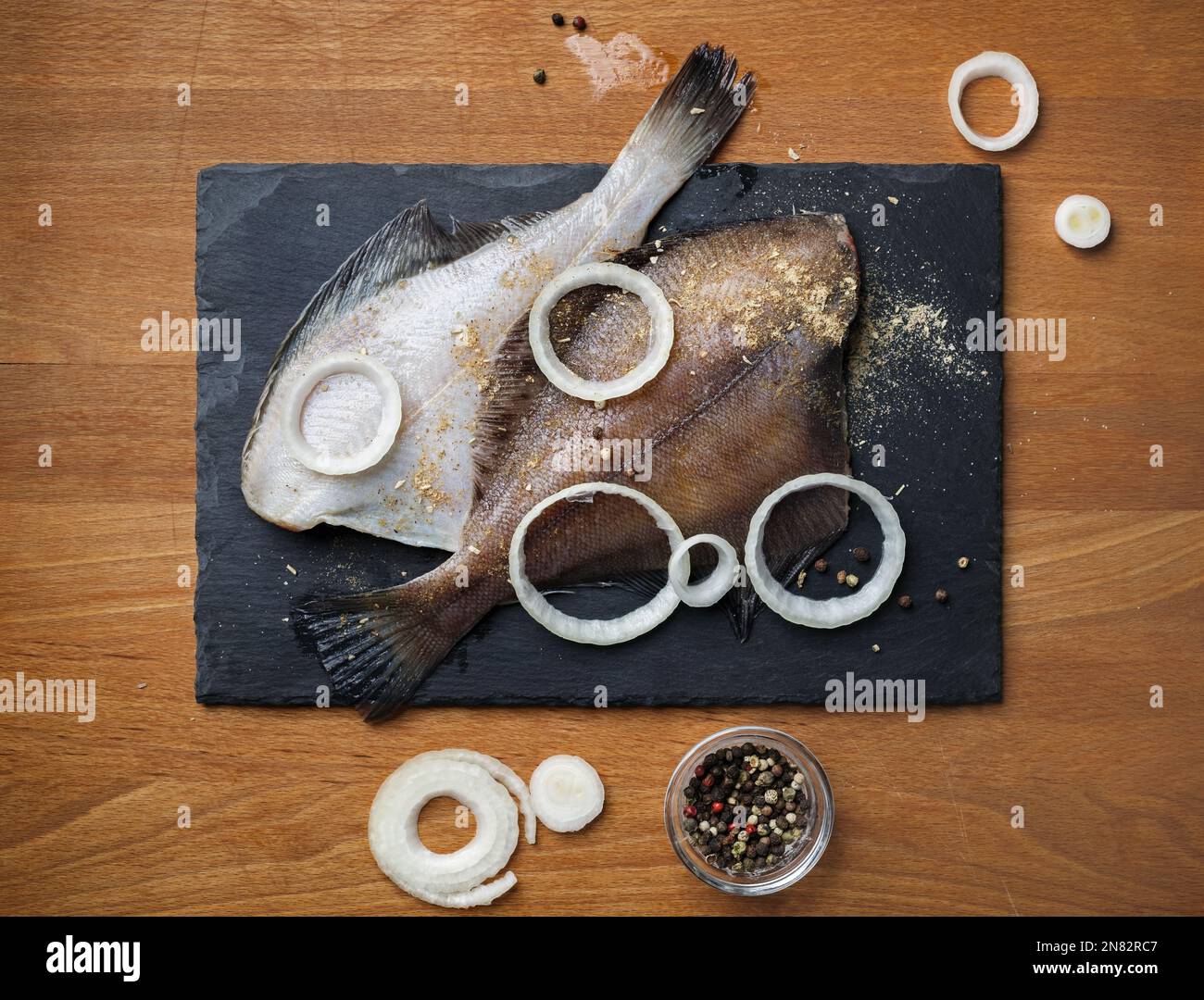 Cooking delicious flounder with spices, pepper and onions. Flat lay ...