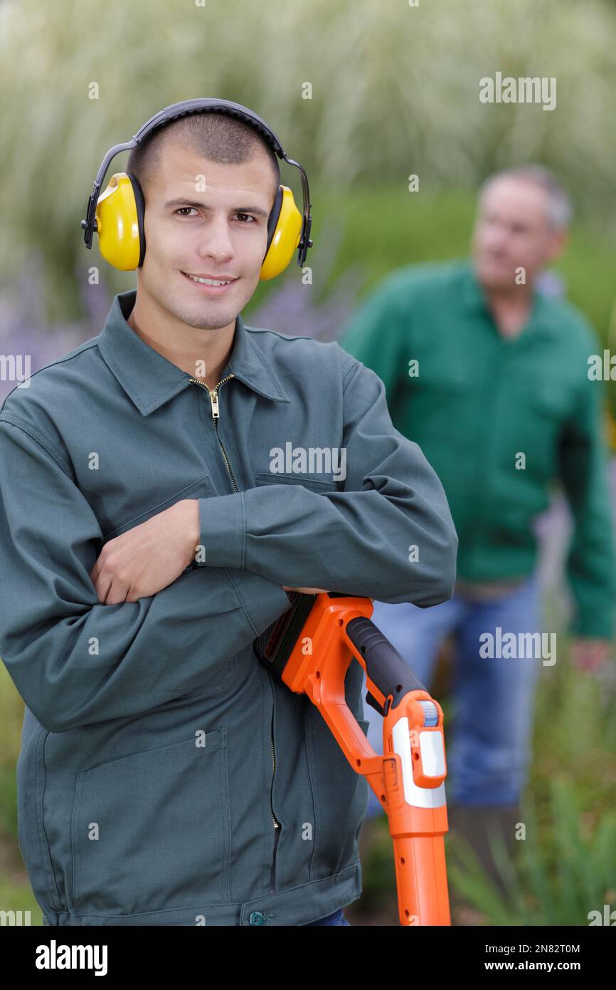 young smiling gardener with crossed arms standing in garden Stock Photo ...