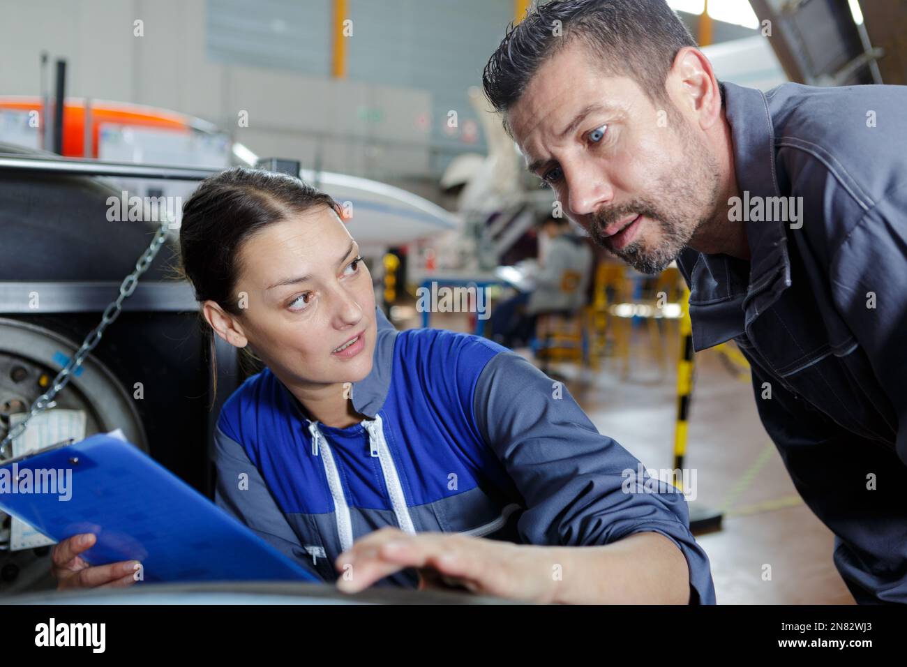 female mechanic with clipboard talking to a male colleague Stock Photo ...