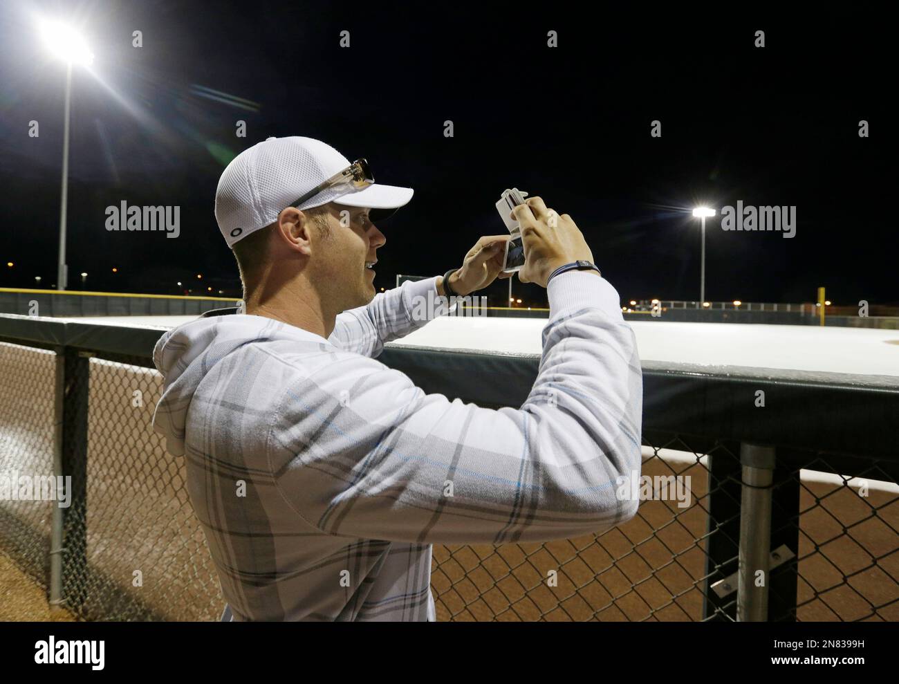 Colorado Rockies' Laris Davis takes photos of a snow covered baseball ...