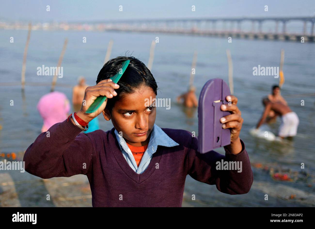 A young Indian Hindu devotee combs his hair after a dip at the Sangam ...