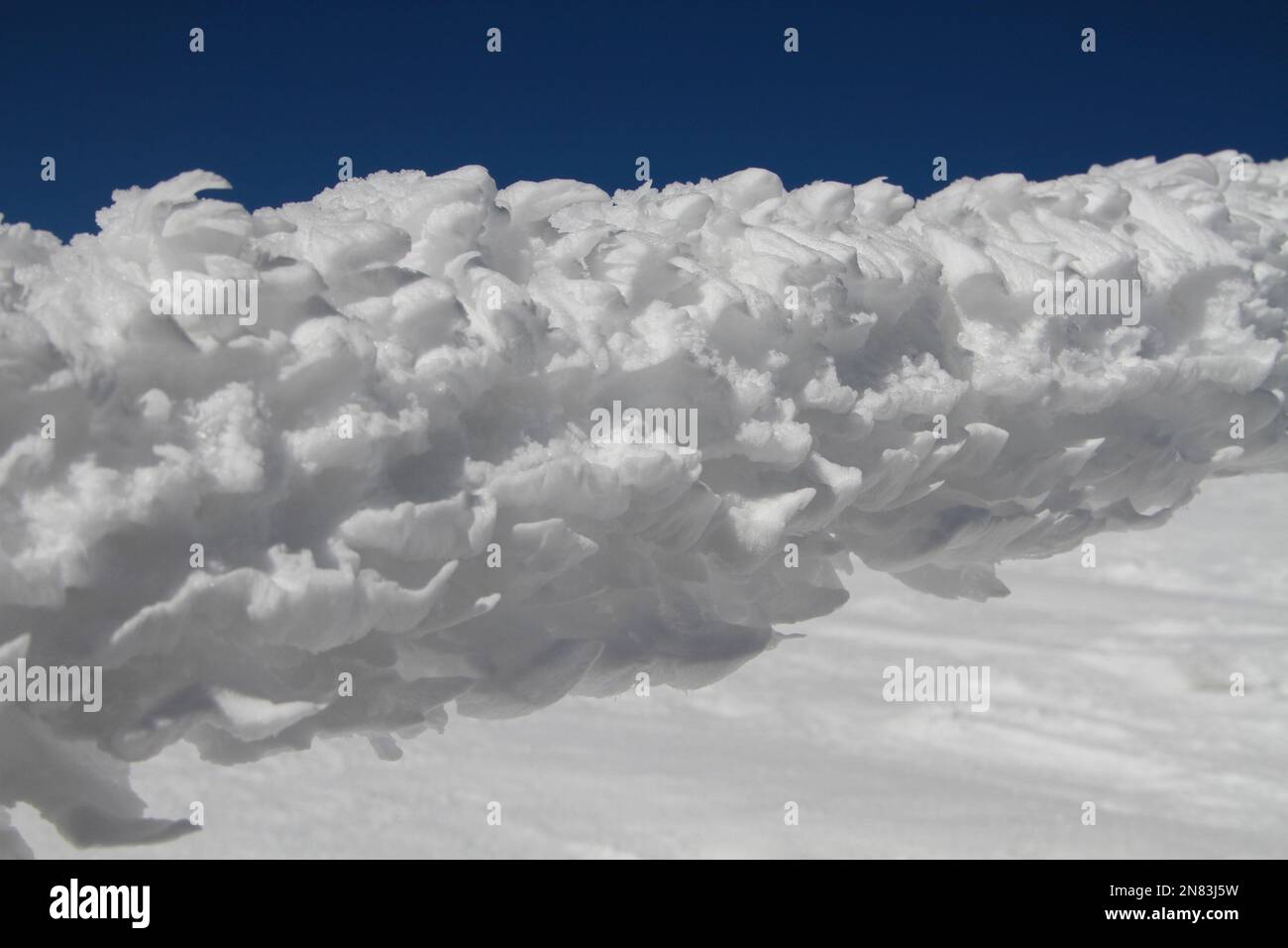 Traces of wind activity. Frozen snow in front of blue sky. White winter ...