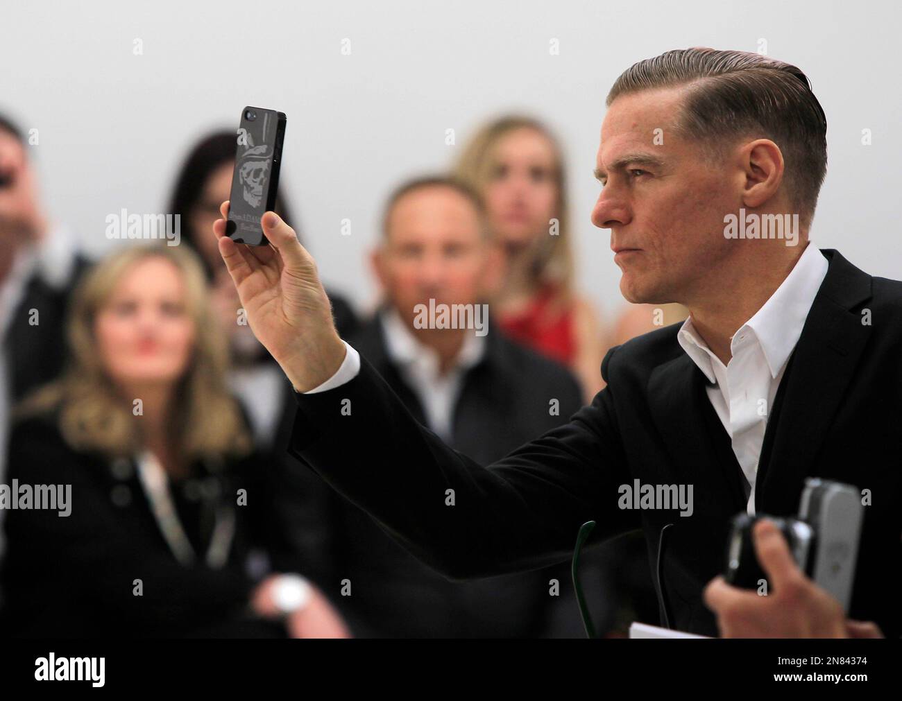 Bryan Adams takes a photograph of a model wearing a design created by ...