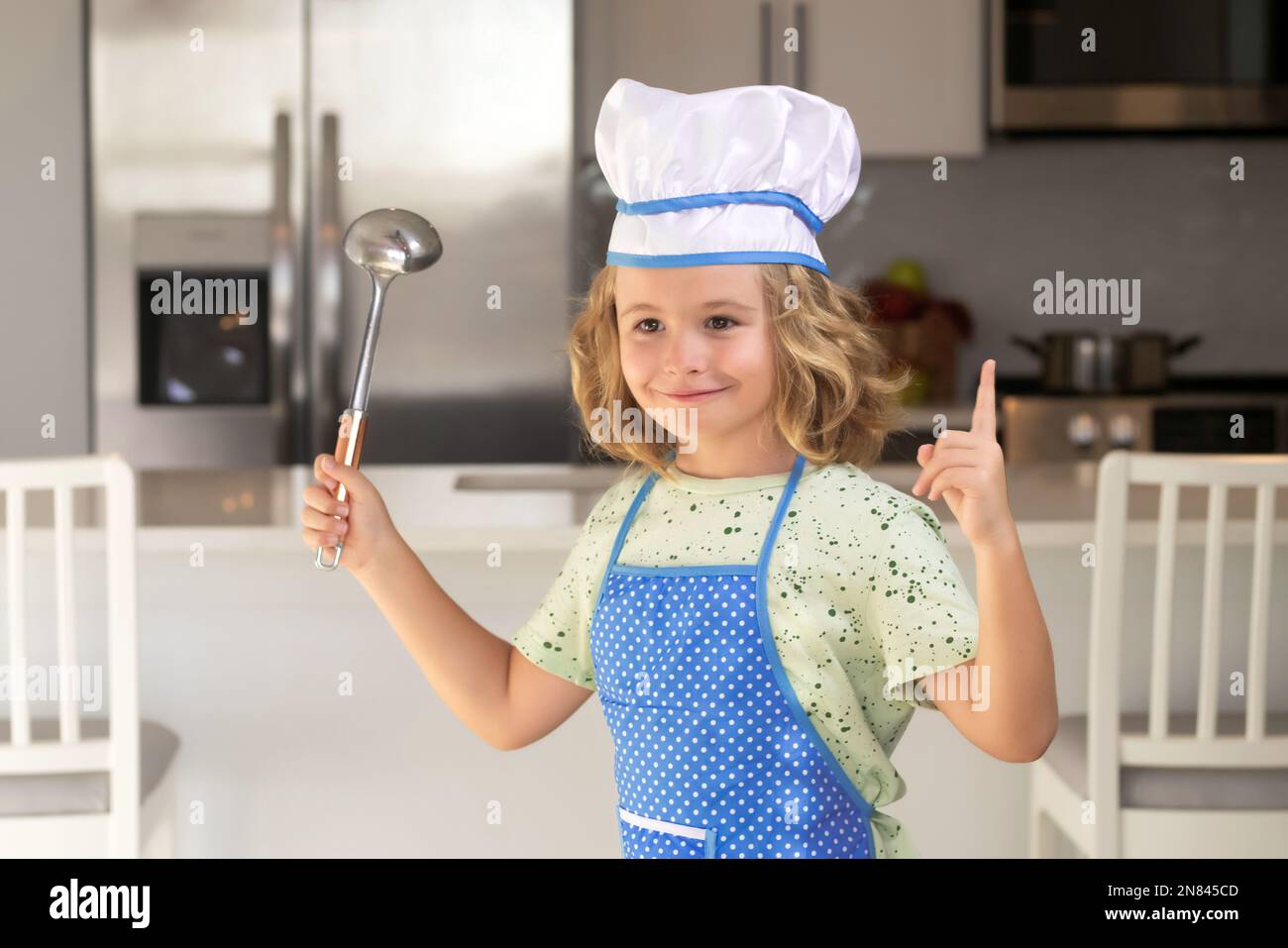 Funny child stand at kitchen table have fun baking, doing bakery ...