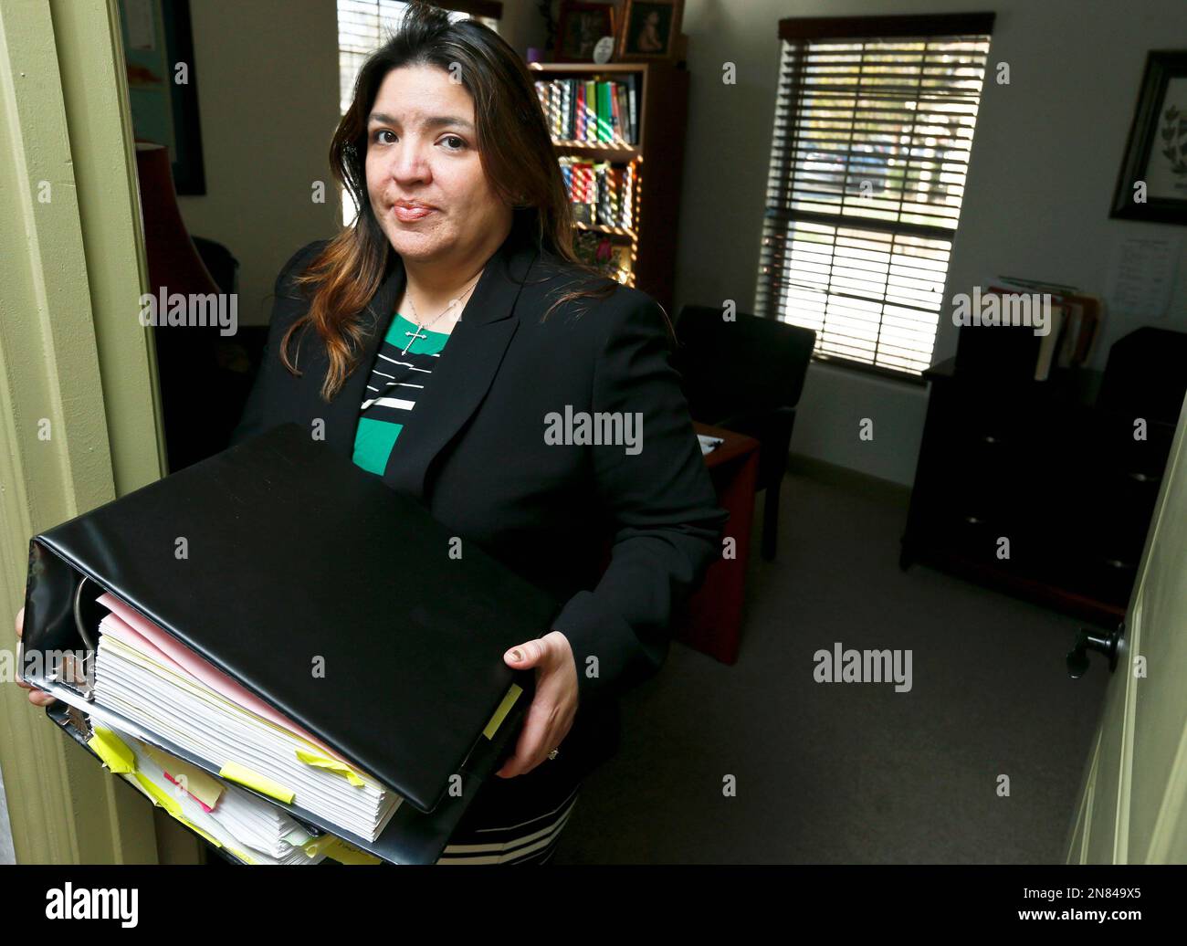 Immigration attorney Delia Salvatierra holds two binders of paperwork ...