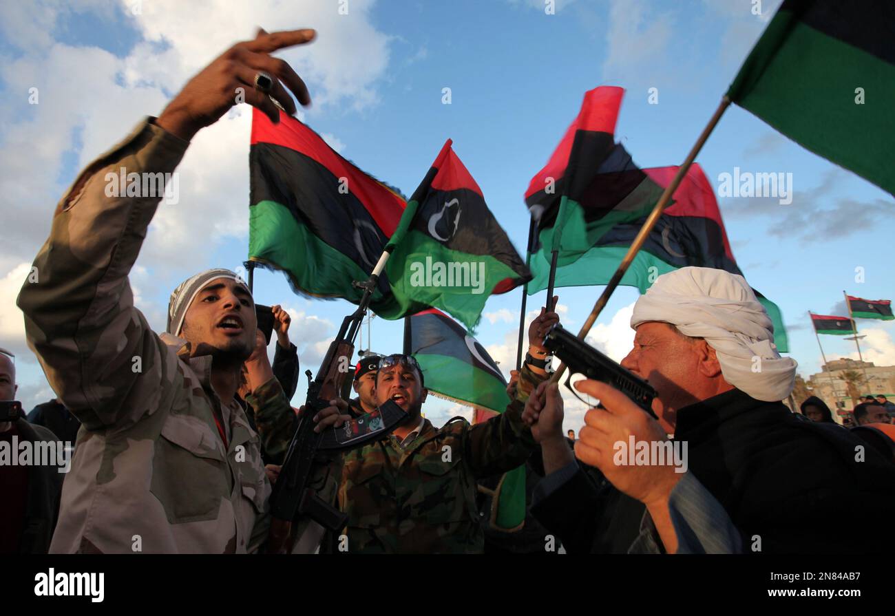Libyans wave the national flags as they chant pro-revolutionary slogans ...